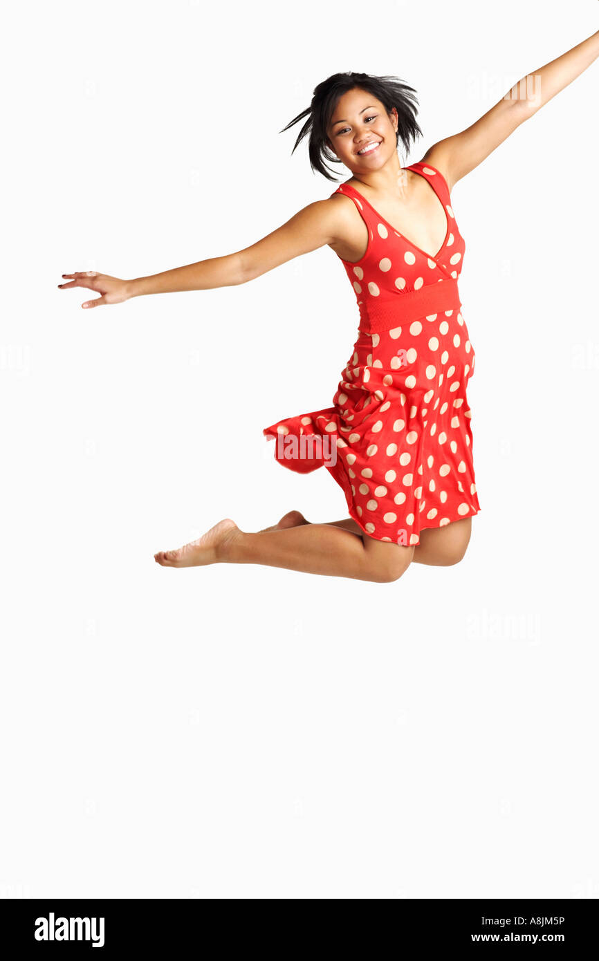 Portrait of a young woman jumping and smiling Stock Photo - Alamy