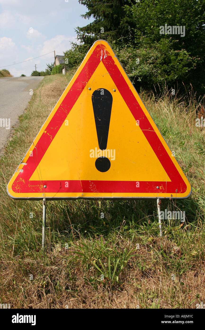 French warning triangle road sign next to rural country lane with blue ...