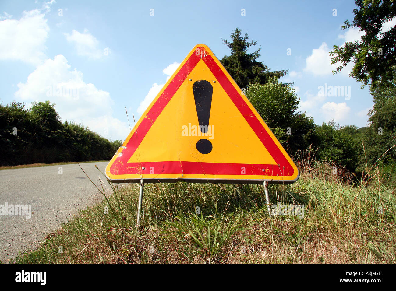 French warning triangle road sign next to rural country lane with blue ...