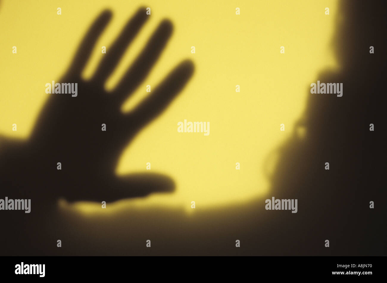 Shadow on cream wall of arm and long hair of a man or woman with hand ...