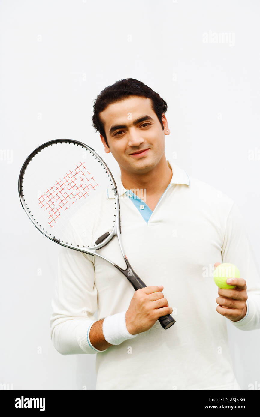 Portrait of a young man holding a tennis ball and a tennis racket Stock ...