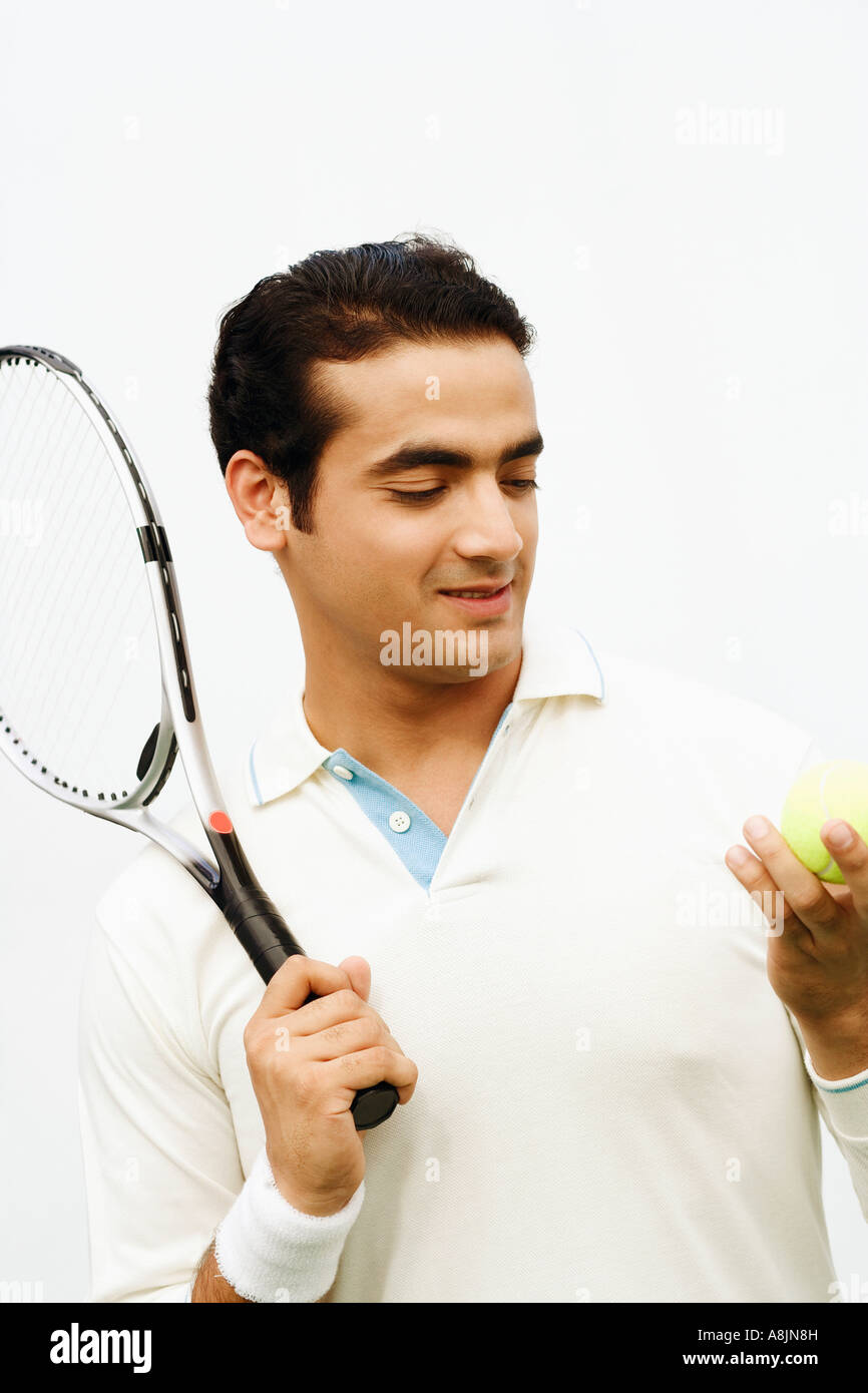 Close-up of a young man holding a tennis ball and a tennis racket Stock ...