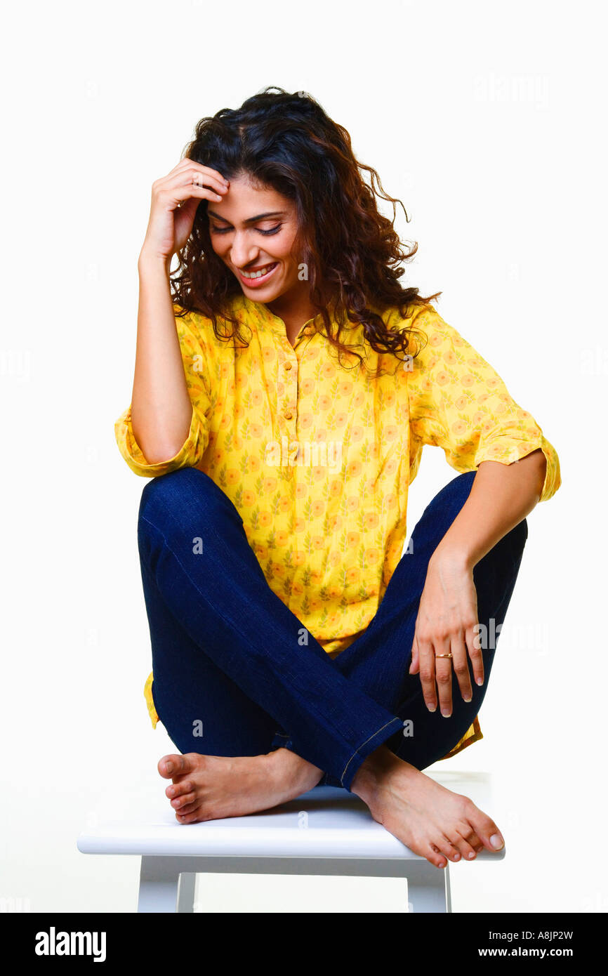 Young woman sitting on stool and smiling Stock Photo - Alamy