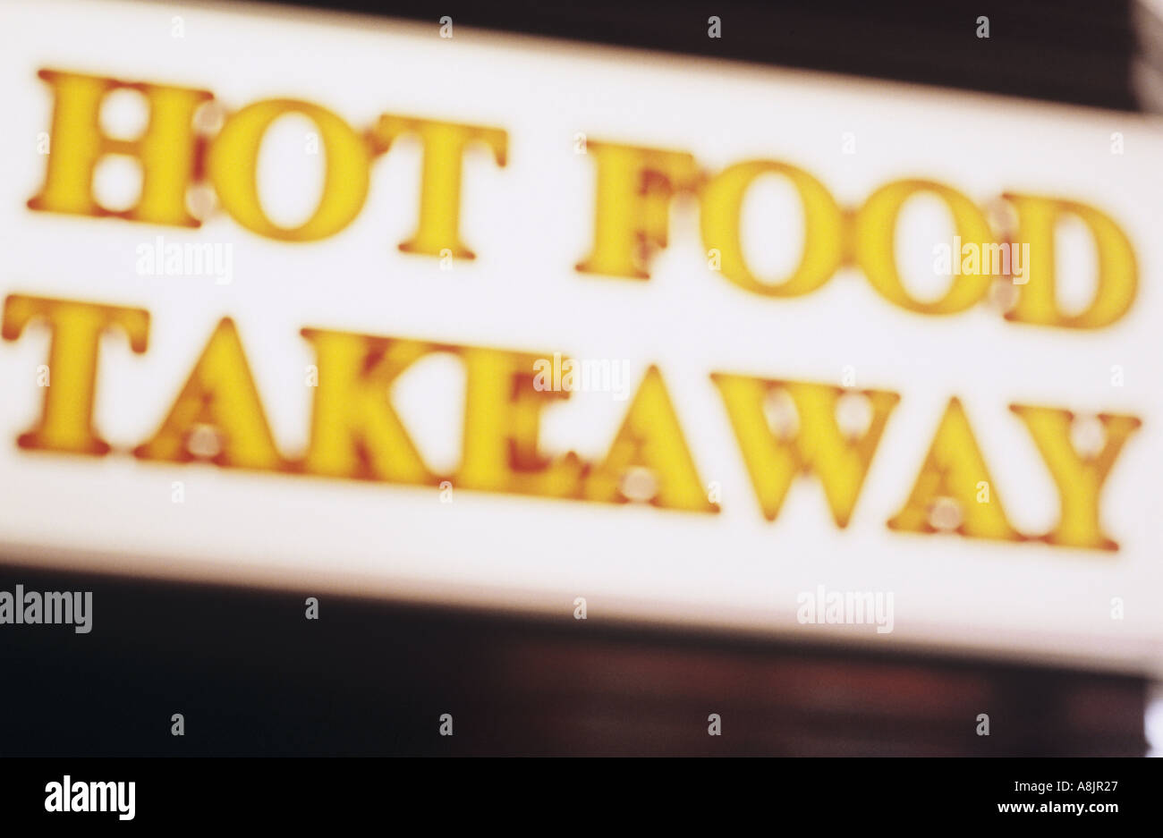 Defocussed yellow and white illuminated sign stating Hot food takeaway ... Defocussed yellow and white illuminated sign stating Hot food takeaway ...
