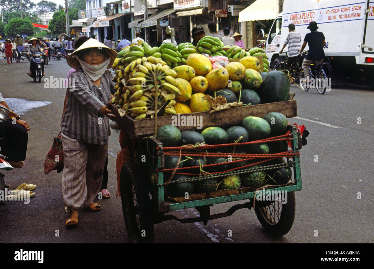 Woman pushing her fruit and vegetable cart to the market in Ho Chi Minh ...