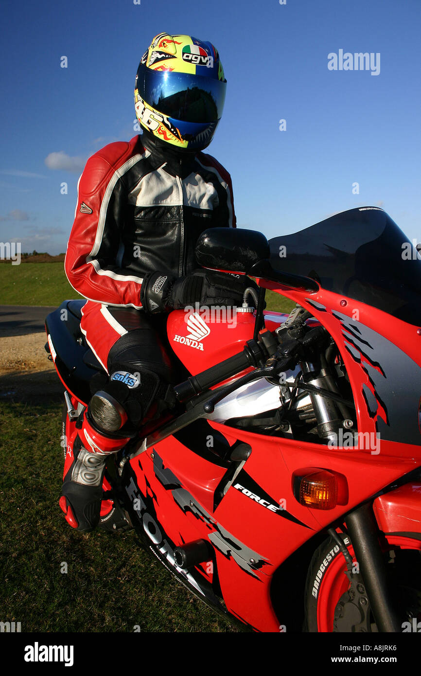 motorbike rider in helmet and leathers sitting on red honda with blue ...