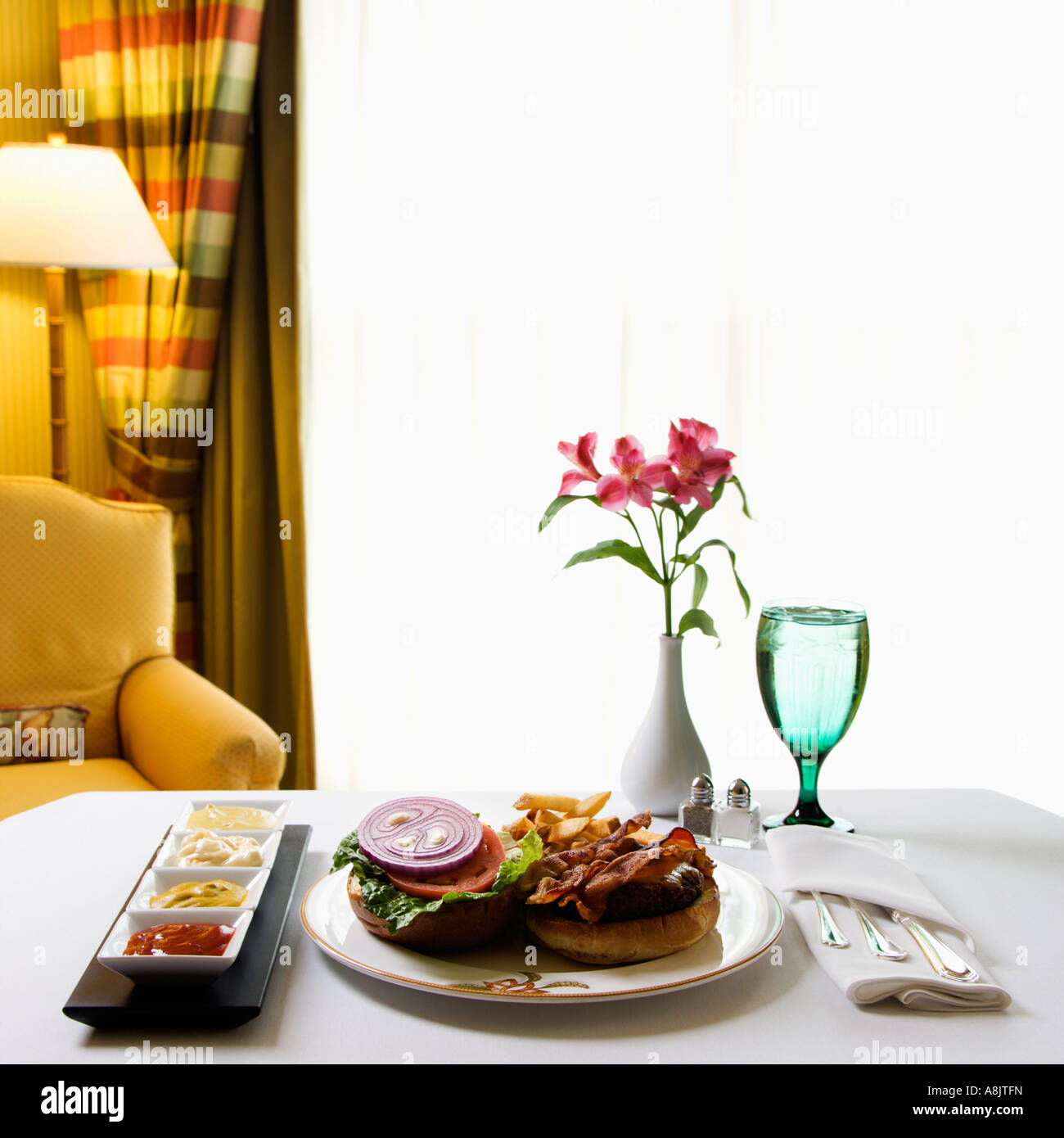 Room service cheeseburger meal with flowers and condiments Stock Photo ...