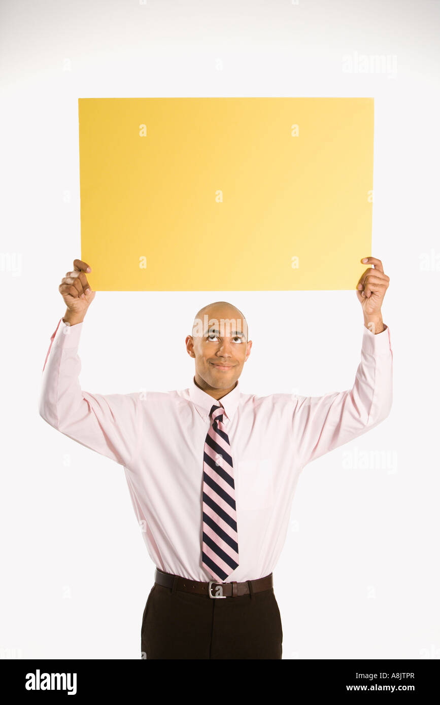 African American man holding blank yellow sign overhead standing ...