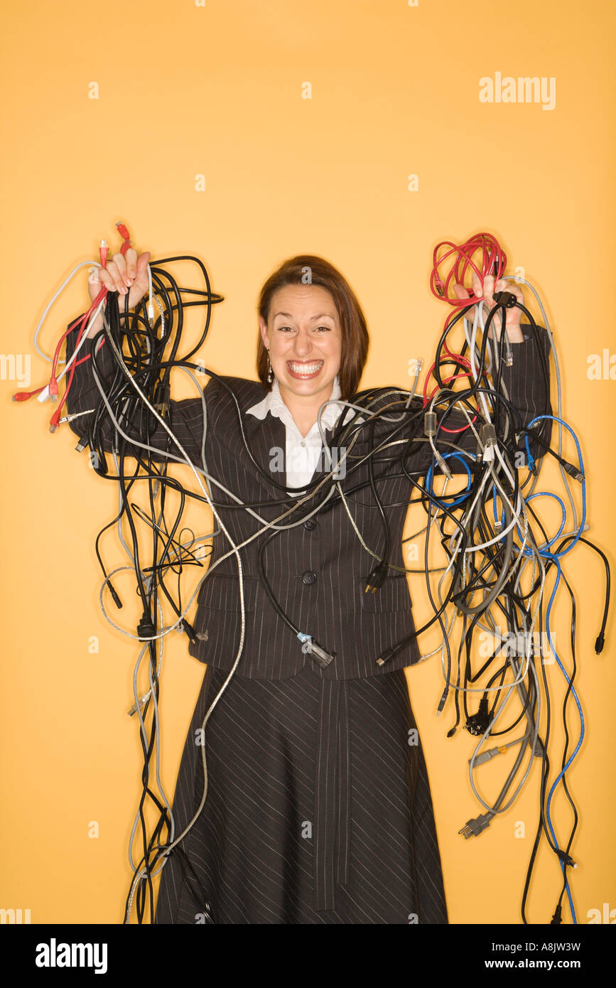 Caucasian businesswoman smiling holding pile of tangled cords and wires ...