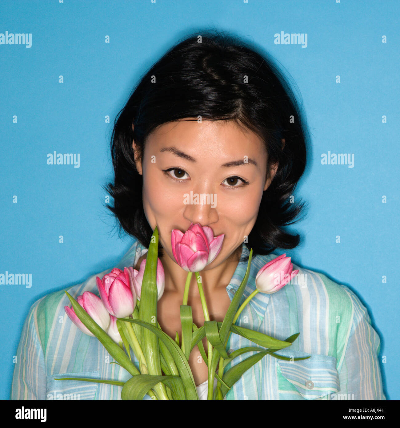 Head and shoulder portrait of pretty Asian mid adult woman smelling ...