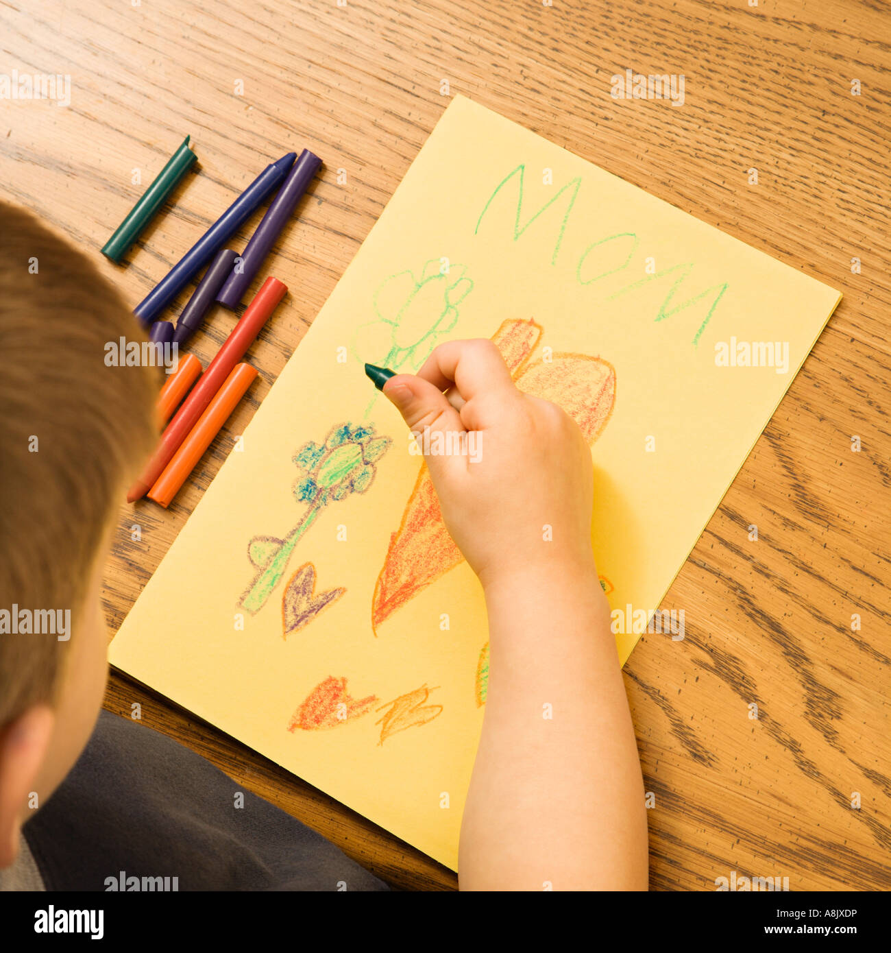 Caucasian boy drawing on paper with crayons Stock Photo - Alamy