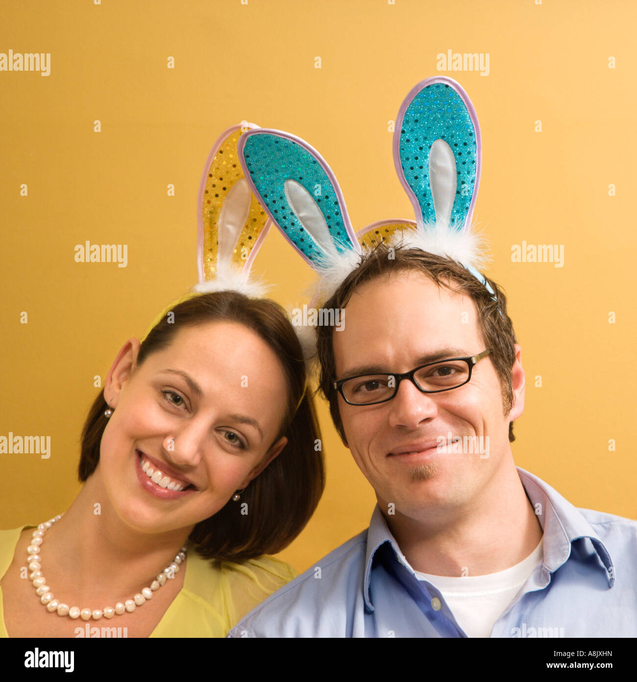 Caucasian mid adult couple wearing rabbit ears and looking at viewer ...