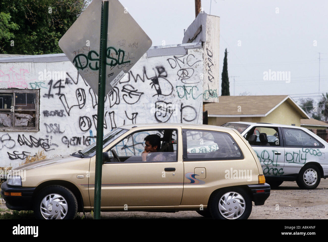 A latino waits outside a gang graffiti covered building during a 1994 ...