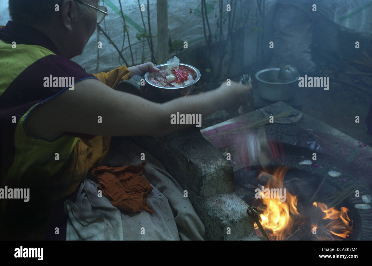 A tantric tibetan buddhist makes a fire puja offering at the end of a ...