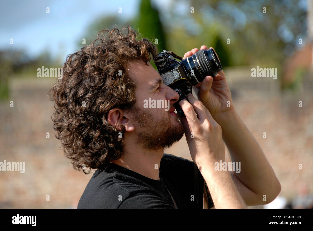 Twenty two year old young man taking photographs with Nikon camera ...