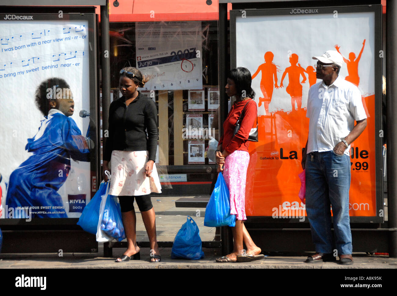 People standing at bus stop waiting Stock Photo - Alamy