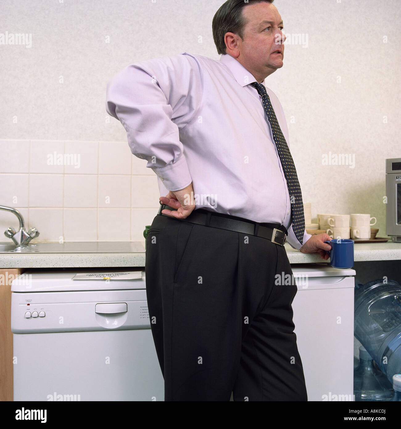 A businessman standing in an office kitchen leaning on the sink Stock ...