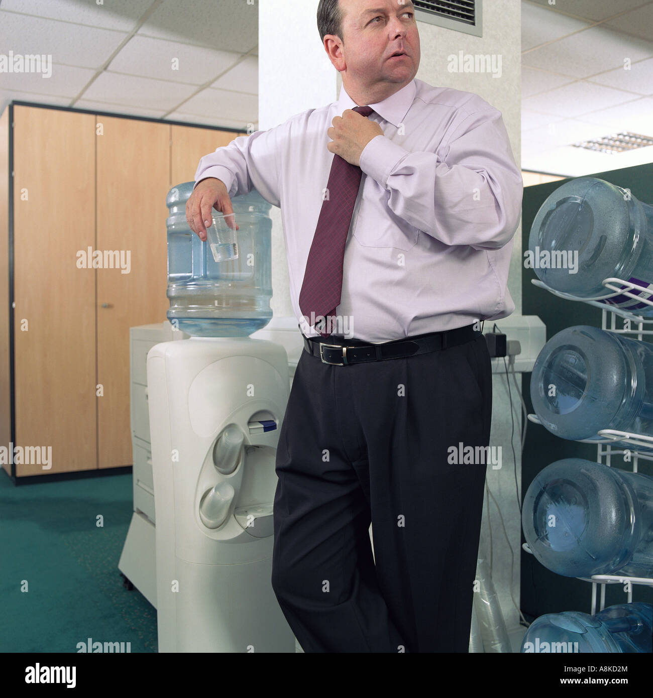 A businessman leaning on a water dispenser Stock Photo - Alamy