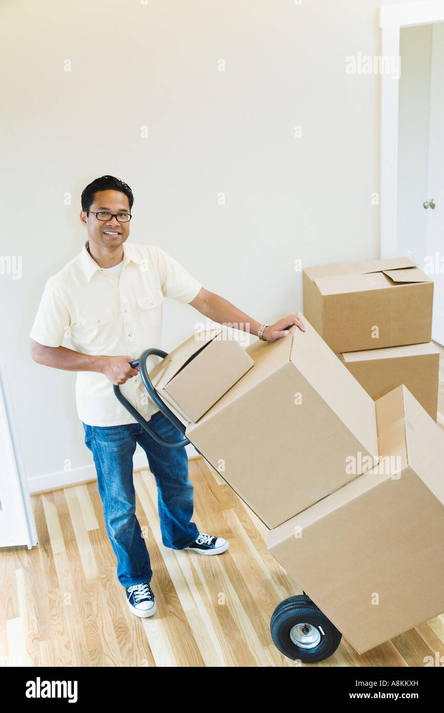 Asian man moving boxes in new house Stock Photo - Alamy