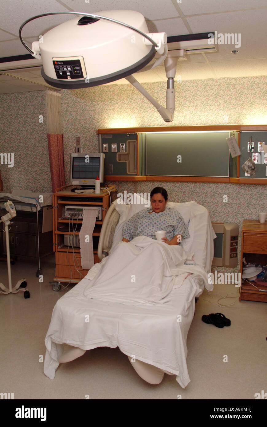 Hispanic-American woman in early stages of labor waits in delivery room ...