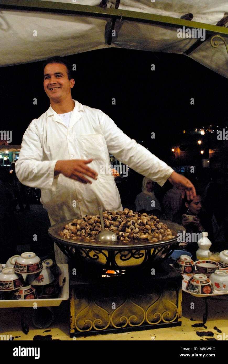 Moroccan man selling cooked snails escargot on food stall at night ...