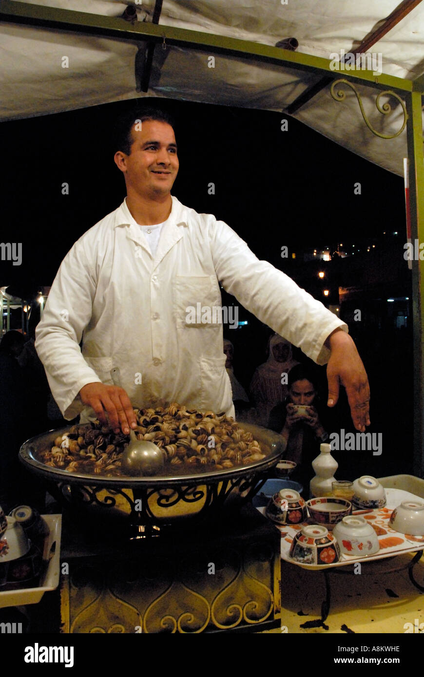 Moroccan man selling cooked snails escargot on food stall at night ...