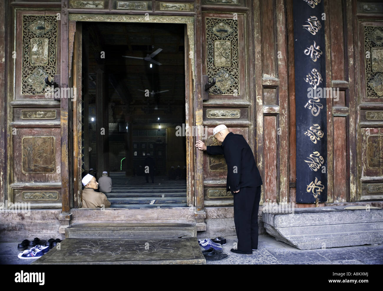 CHINA XI AN Chinese Muslim man removing his shoes as other men pray ...