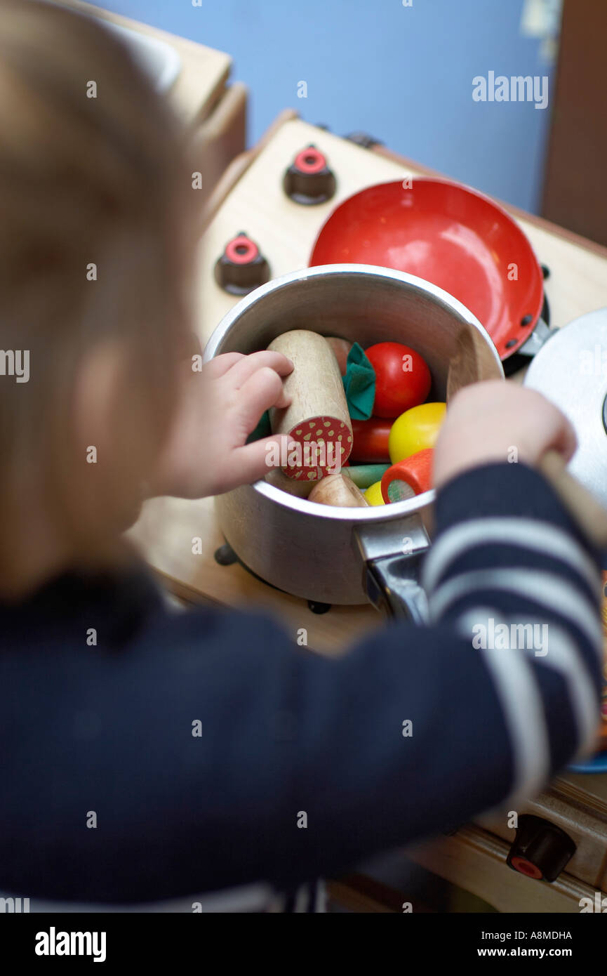 Young girl child playing with cooking pot and cooker toys in nursery ...