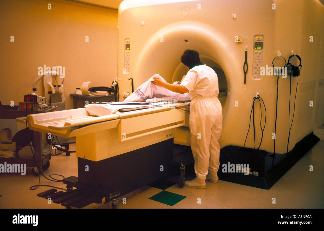 Medical technician adjusting a Magnetic Resonance Imaging MRI machine ...