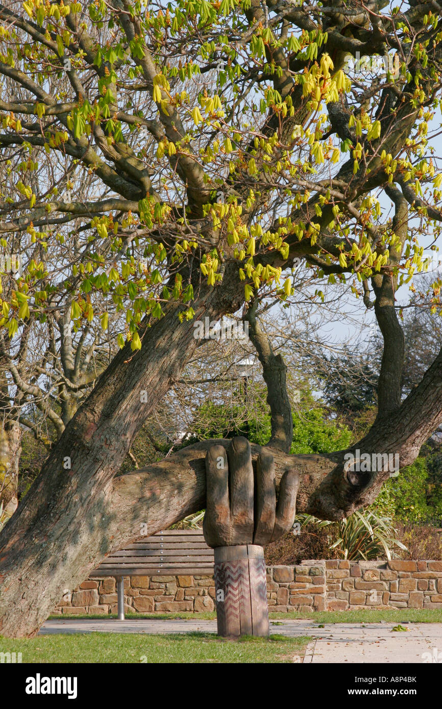 Leaning chestnut tree supported by sculptured wooden hand on quayside ...