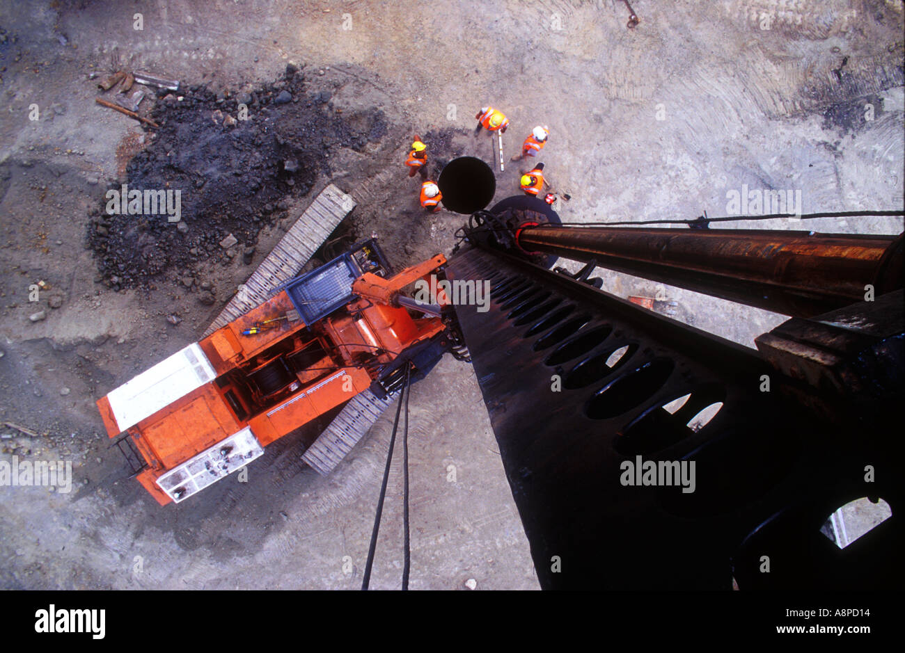 Construction workers look into a piling hole Construction workers look ...