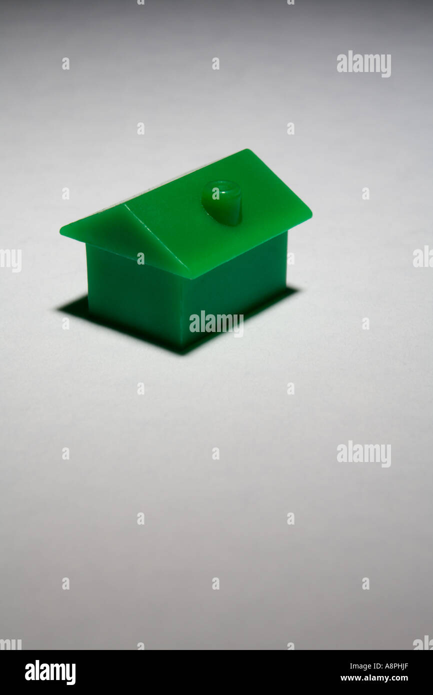1 single green monopoly house standing all alone on a white surface ...