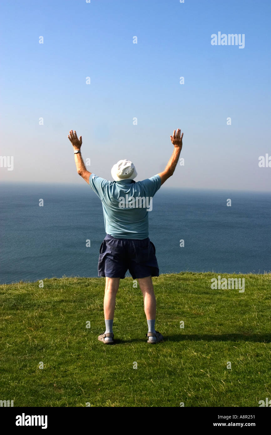 Old Man on Clifftop with Arms Aloft Facing Out to Sea Stock Photo - Alamy