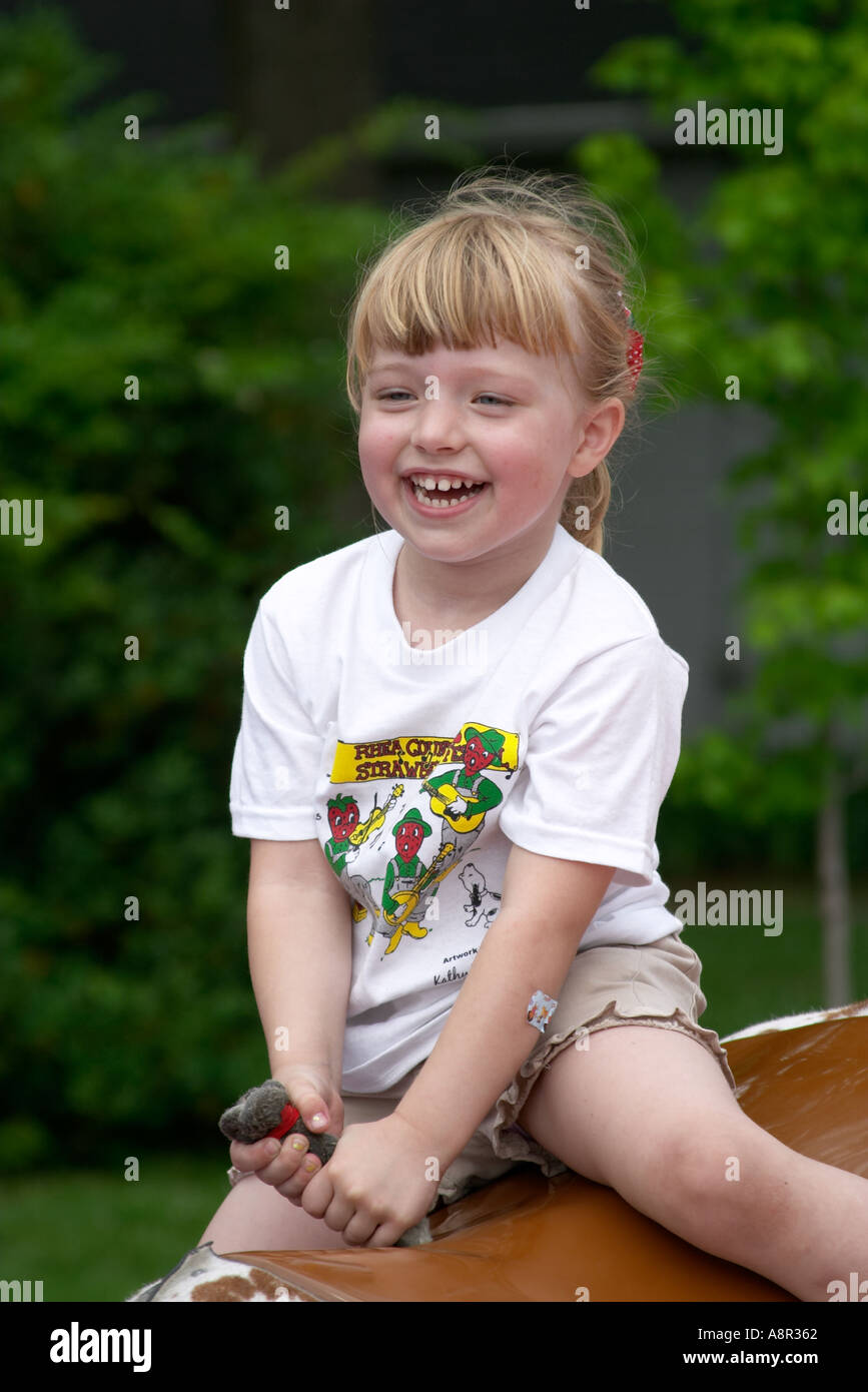 A little girl riding a mechanical bull at the East Tennessee Strawberry ...
