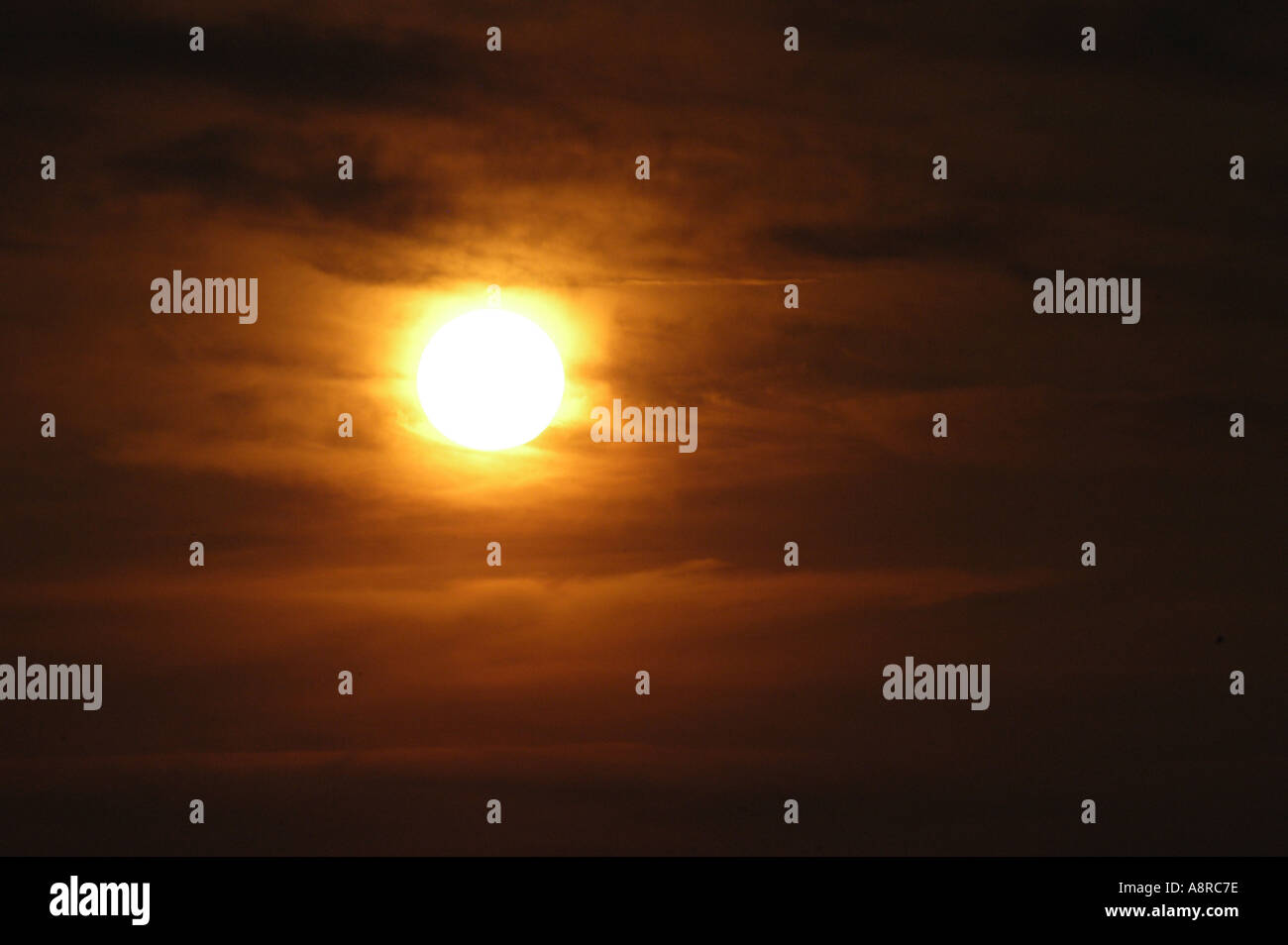 Bright white and yellow sun in darkened sunset sky Stock Photo - Alamy