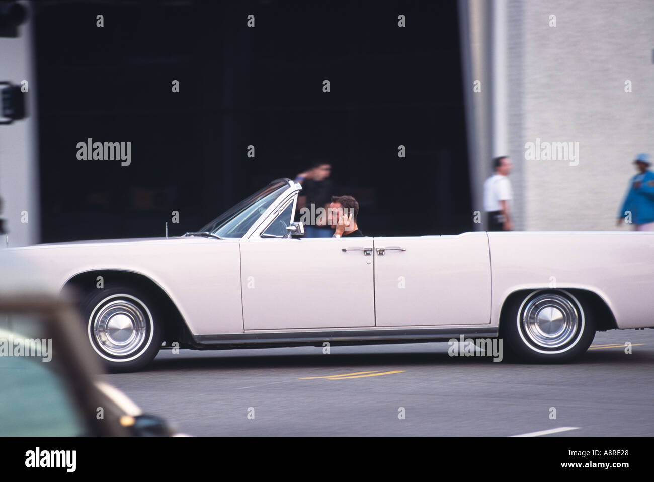 A man talking on a mobile phone whilst driving a white limo on ...