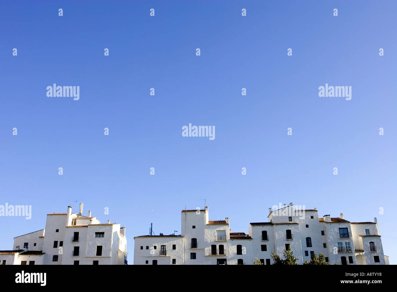Sunny blue skyline of rows of white pueblo apartment blocks in Spain ...