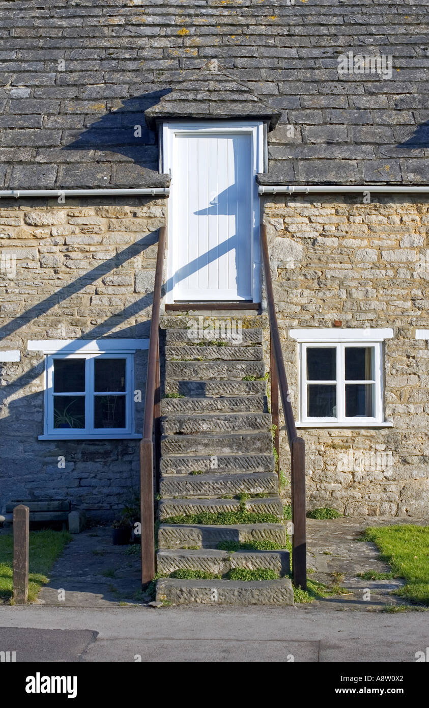 Traditional stone clad house with stone steps leading to the road on a ...