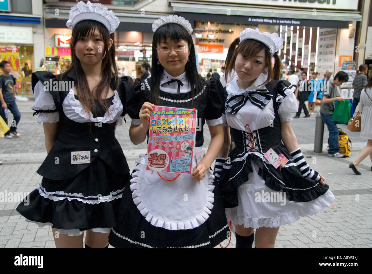 Young girls in maids costumes on street advertising Maids cafe in ...