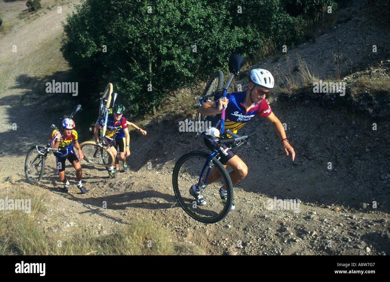 Mountain Bikers Carrying Their Bikes Up A Steep Slope Stock Photo - Alamy