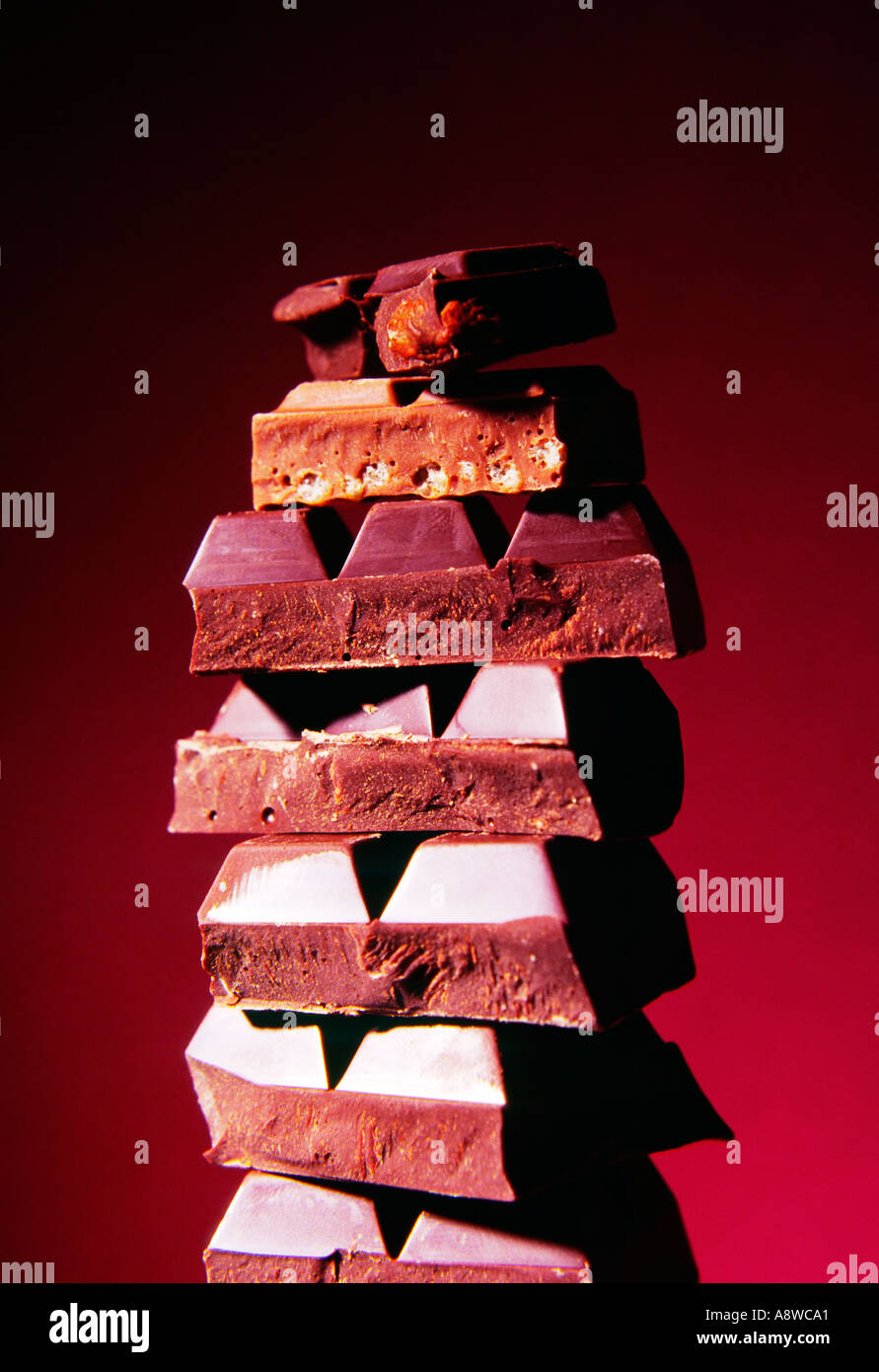 Top tip of a tall stack of broken chocolate bar pieces on deep red ...