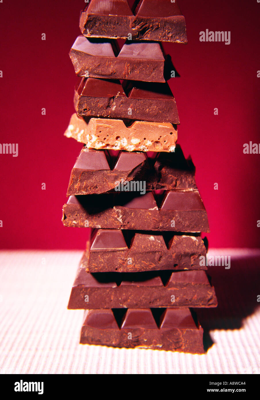 Base of a tall stack of broken chocolate bar pieces on deep red ...