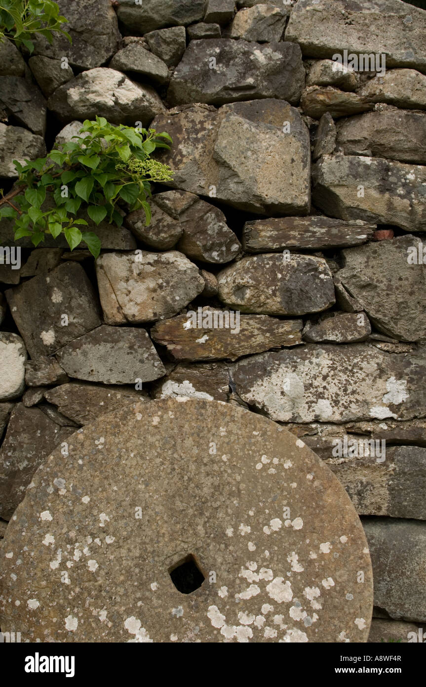 Old millstone resting against stone wall near Dolgellau Gwynedd north ...