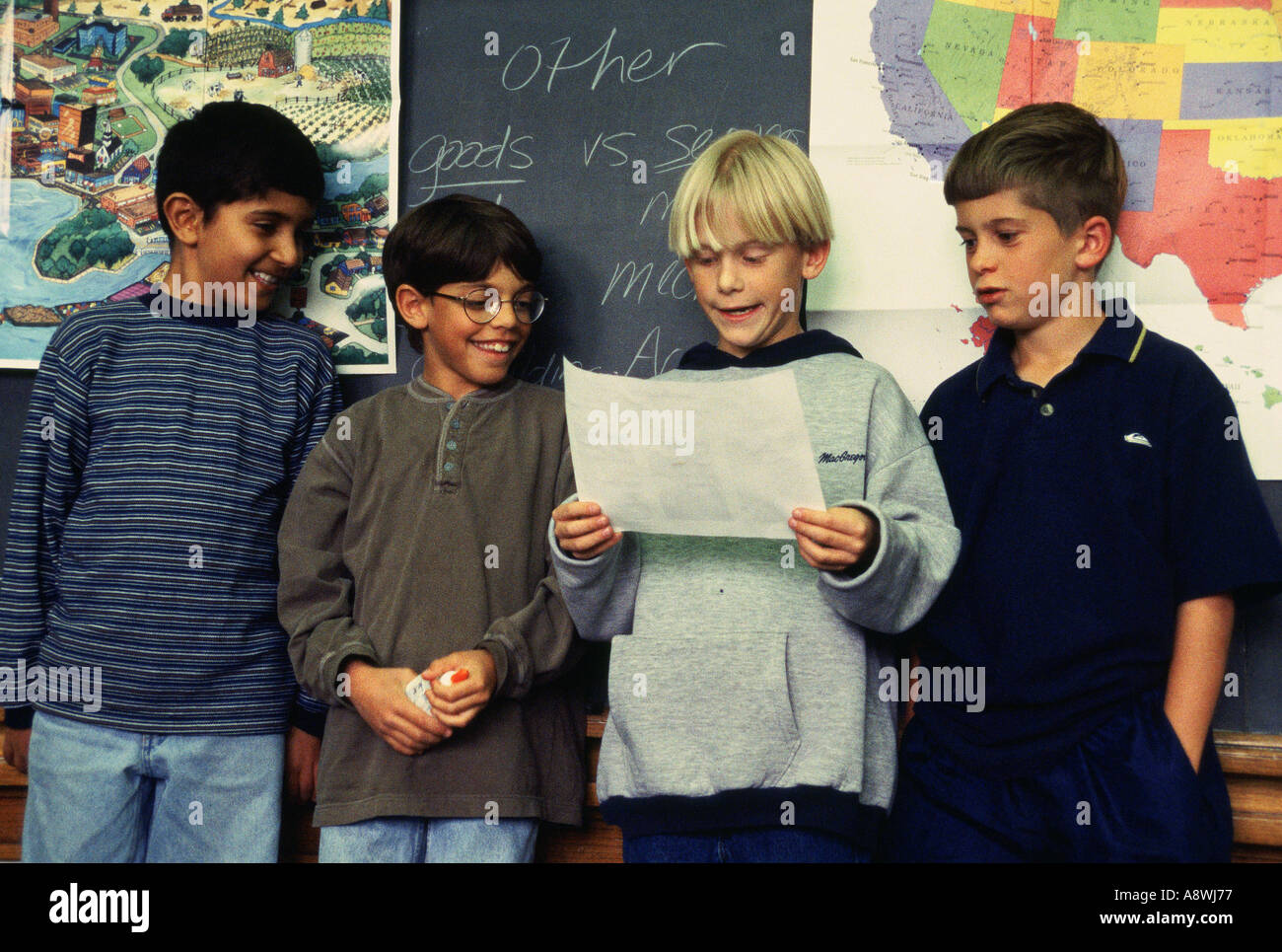 Fourth grade boys standing in front of the blackboard making a ...