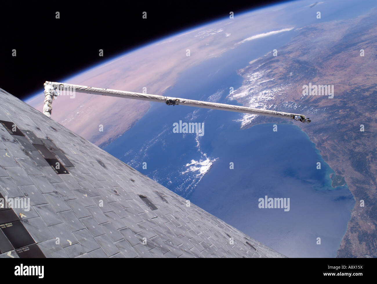 The extendable arm of the space shuttle with the Earth in the ...
