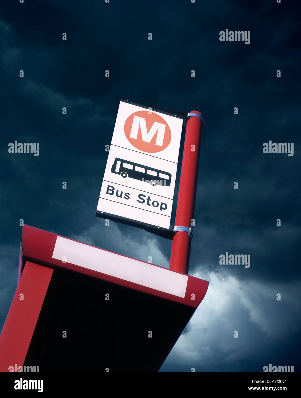 RED BUS SHELTER AND BUS STOP SIGN AGAINST CLOUDS IN STORMY BLUE SKY ...