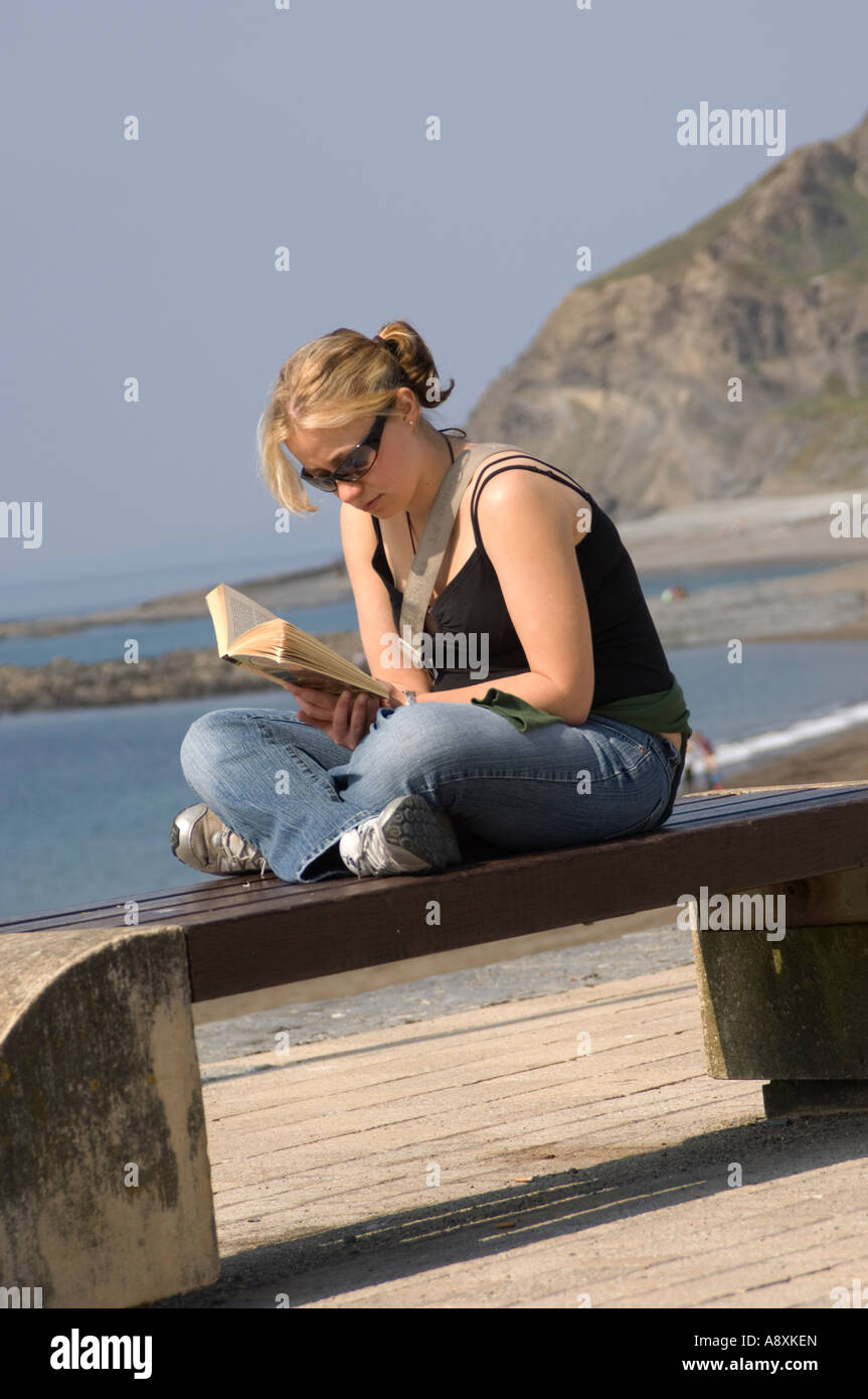 Young Woman student sitting on bench Aberystwyth promenade reading a ...