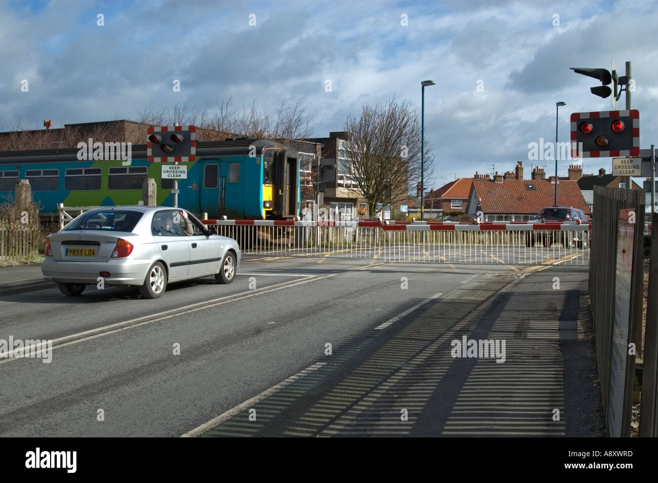 Commuter train passing over a level crossing at Filey North Yorkshire ...