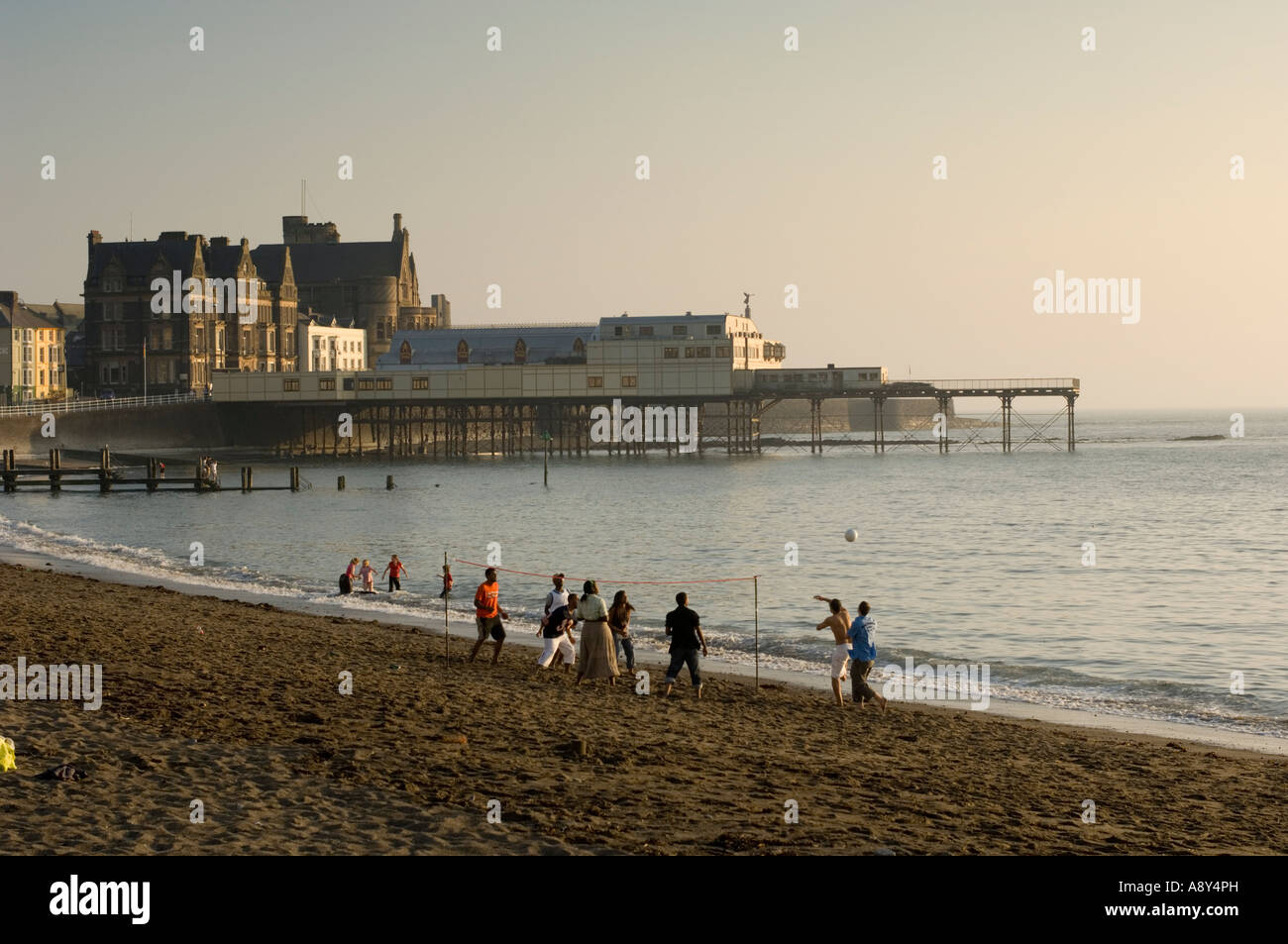 People playing volleyball on Aberystwyth beach at dusk with the Pier ...