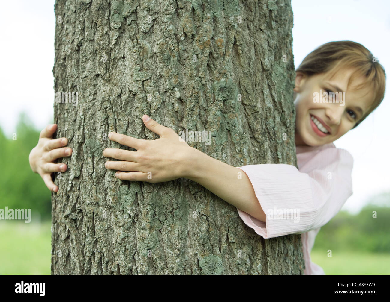 Girl hugging tree and smiling Stock Photo - Alamy